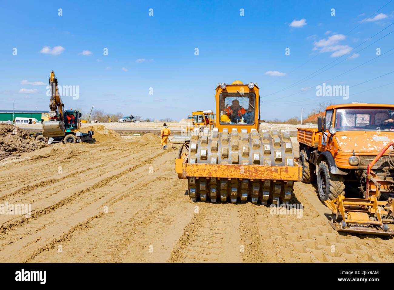 Road roller with spikes and truck with mounted plate vibration ...