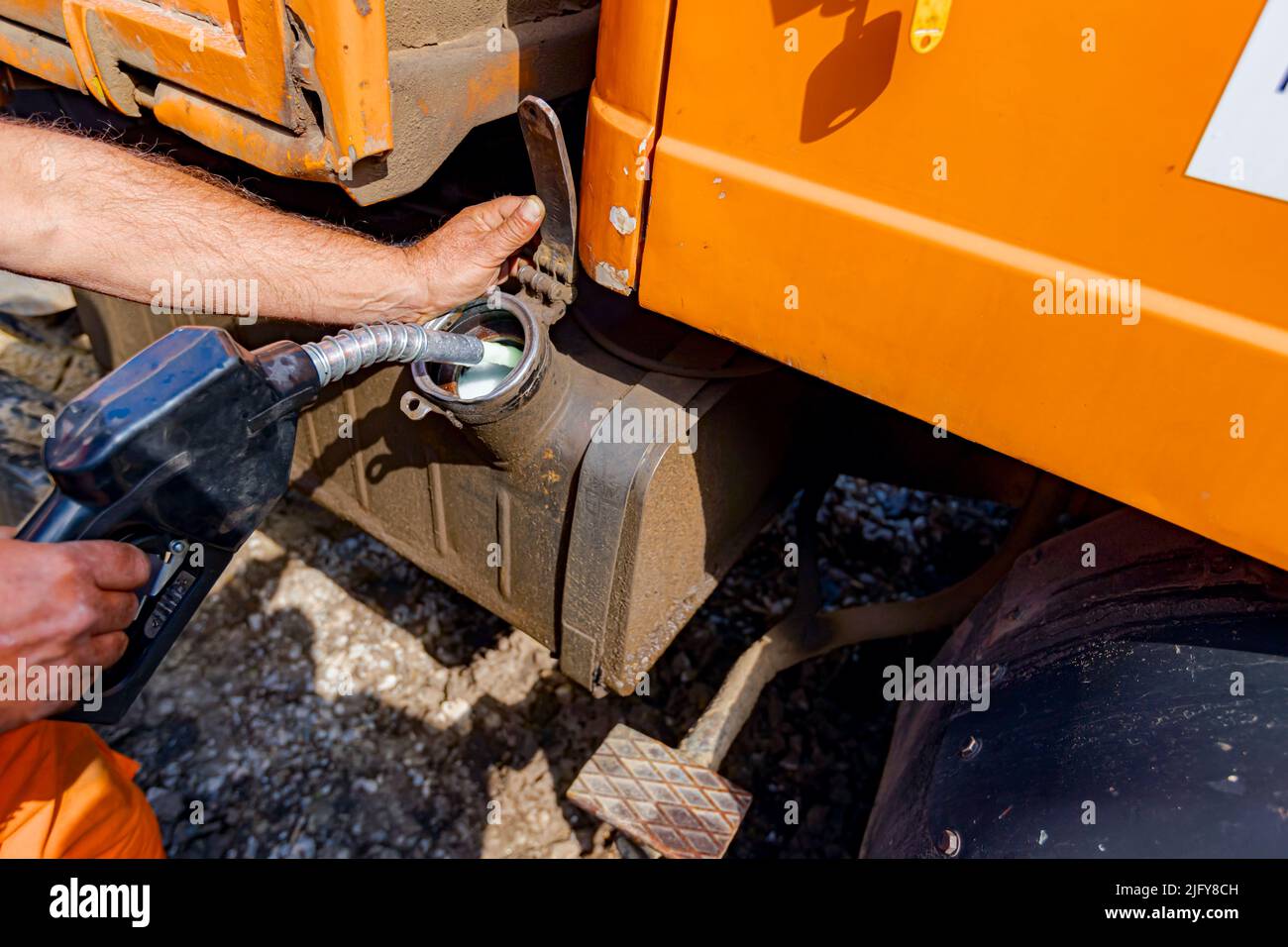 Fuel pump gun inserted in the reservoir of construction machine, pour ...