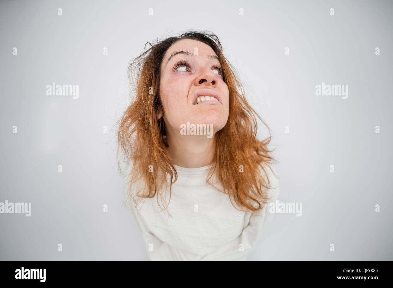 Close-up portrait of insane woman in straitjacket on white background ...