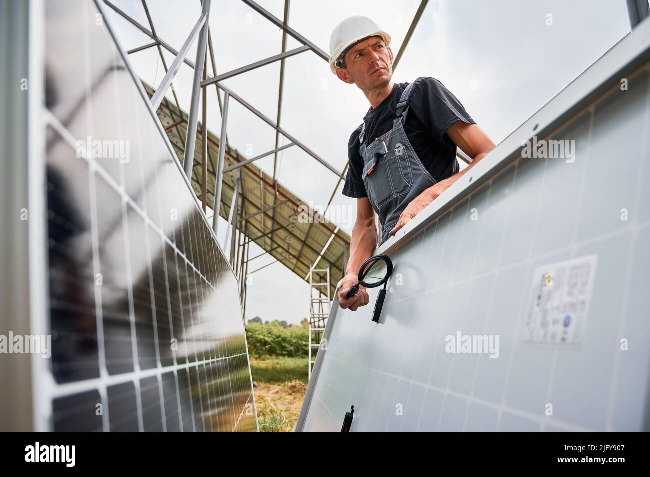 Serious man solar installer assembling photovoltaic solar panel system ...
