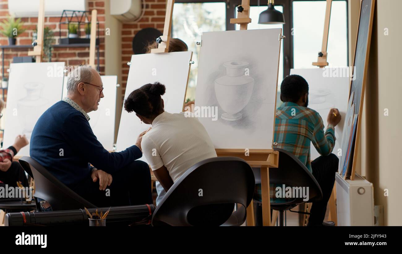 Senior student talking to young woman about drawing lesson, using ...