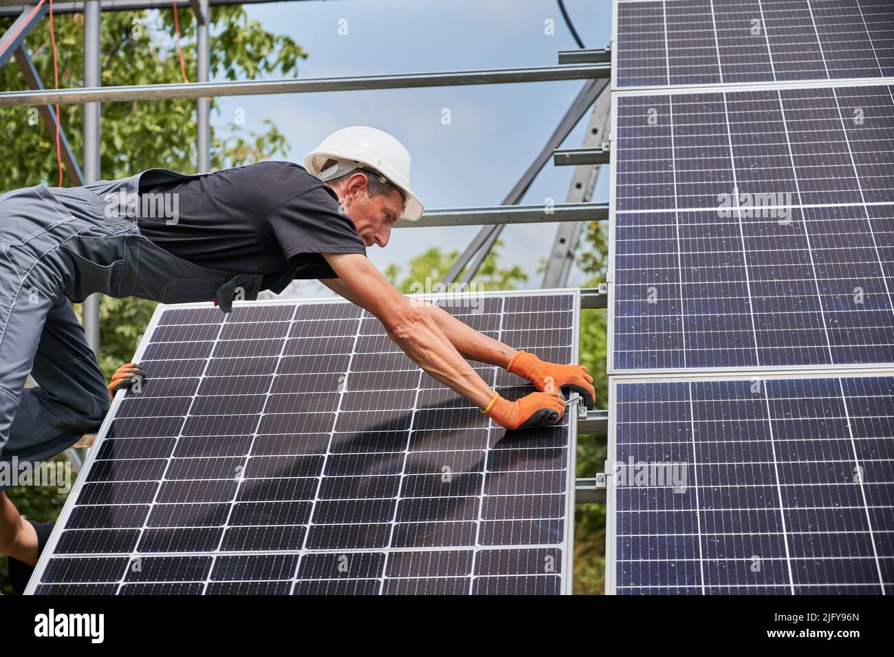 Cropped view of man solar installer placing solar module on metal rails ...