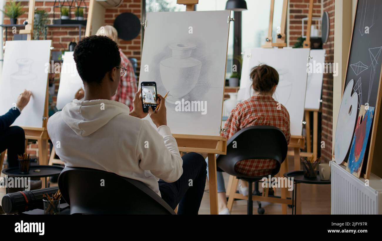 Creative student taking picture of vase sketch on smartphone in art ...