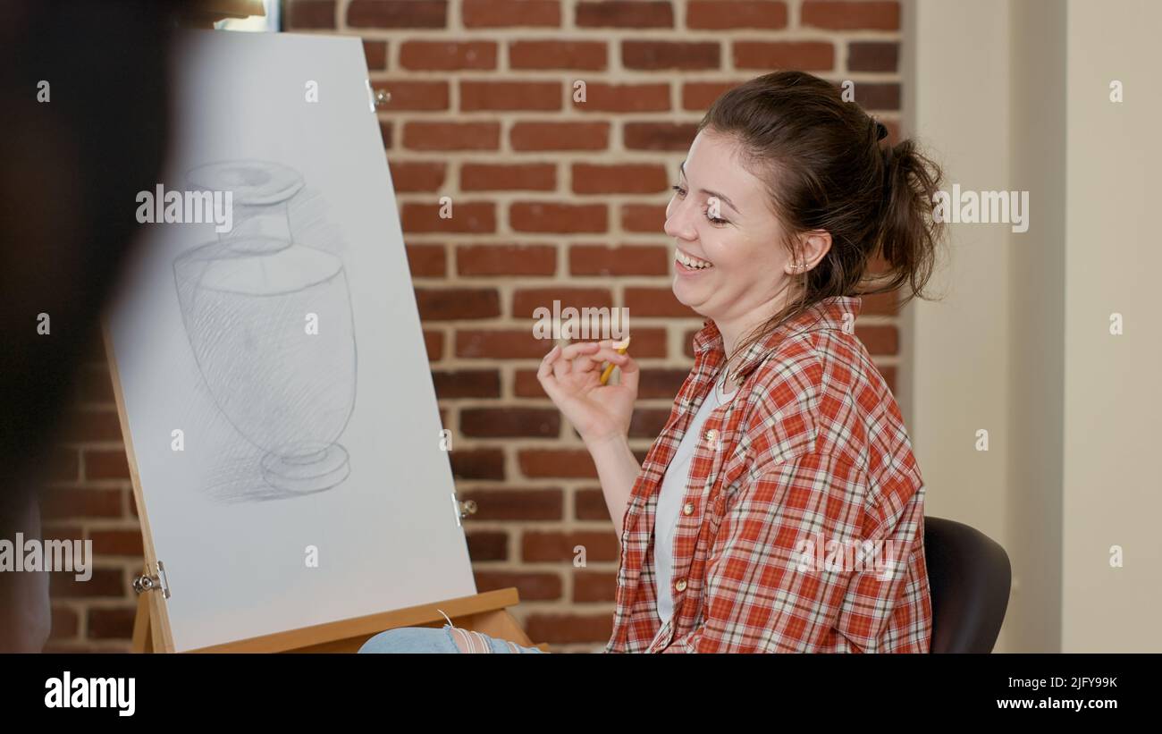 Young woman laughing and having fun at art lesson practice, drawing ...