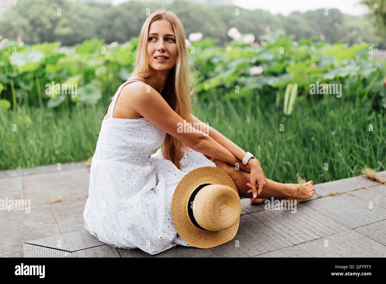 Portrait of beautiful stylish blonde millennial woman posing outdoor. Young woman walking alone ...