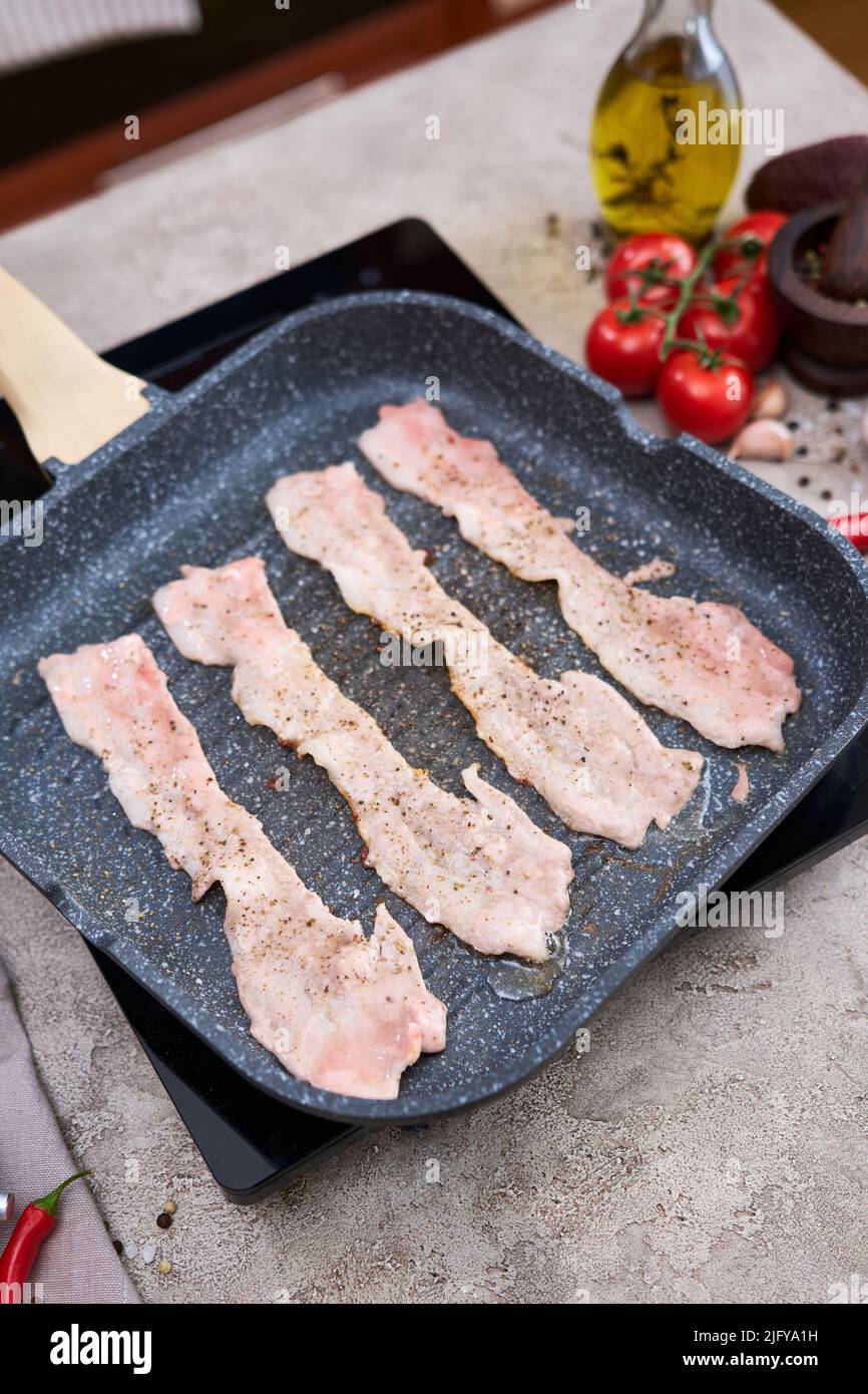 Bacon Being Cooked in grill frying pan Skillet at domestic kitchen ...