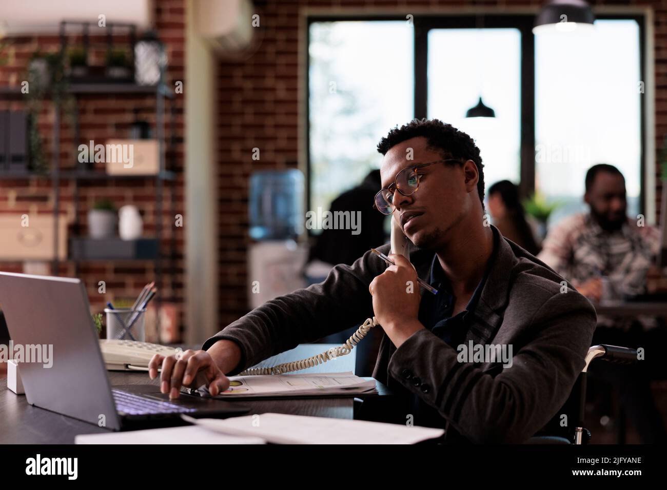 Company employee with physical disability talking on landline phone ...