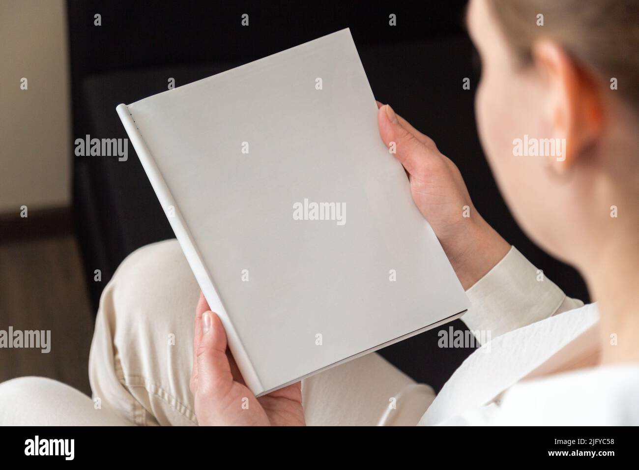 Beautiful female hands hold an open book or magazine in a room on a ...