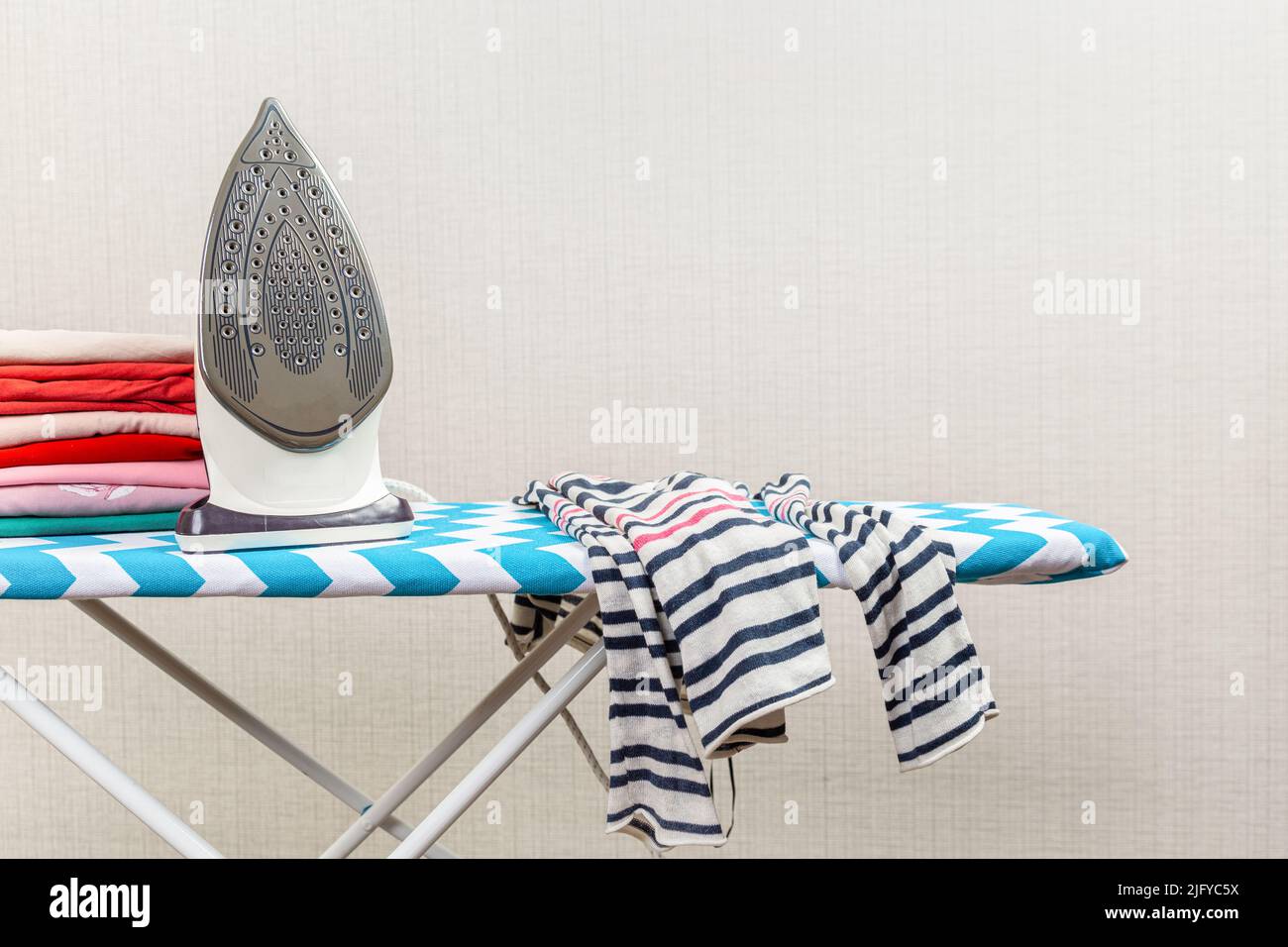New modern iron and clean clothes on board indoors. Laundry day Stock ...