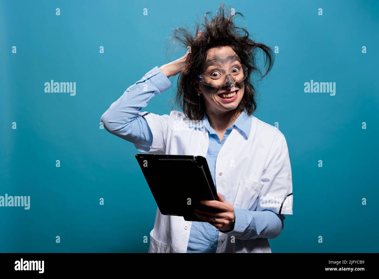 Nutcase biochemist with messy hair and dirty face having tablet looking ...