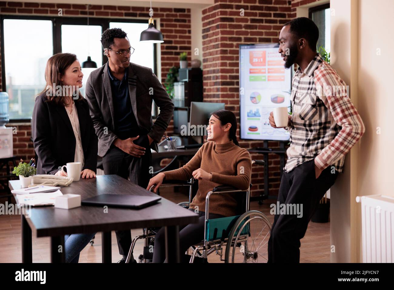 Happy businesspeople talking on break in disability friendly office ...