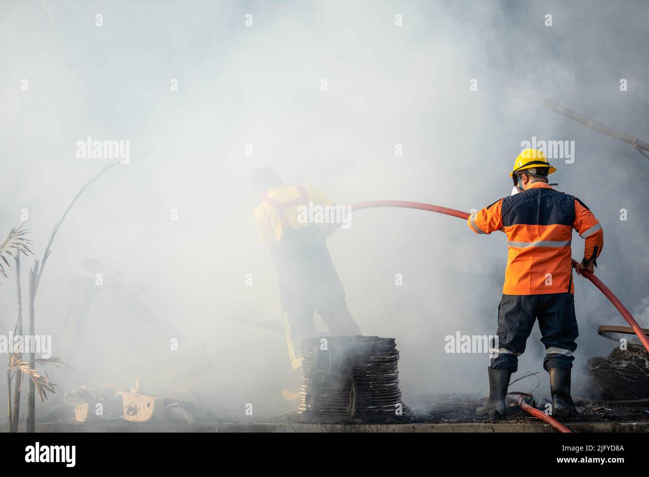 Fireman or firefighter spraying water from big water hose to prevent ...