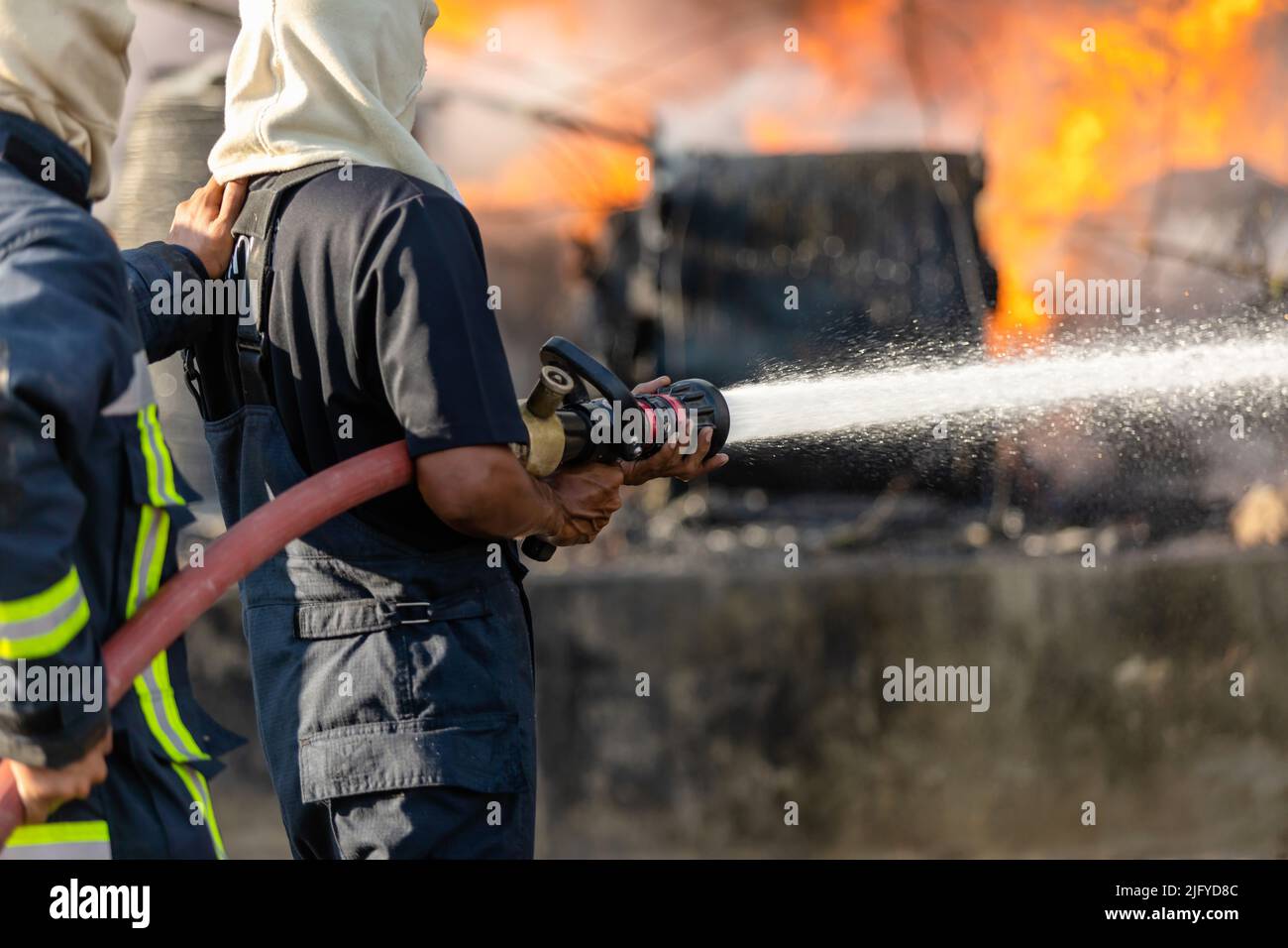 Fireman or firefighter spraying water from big water hose to prevent ...