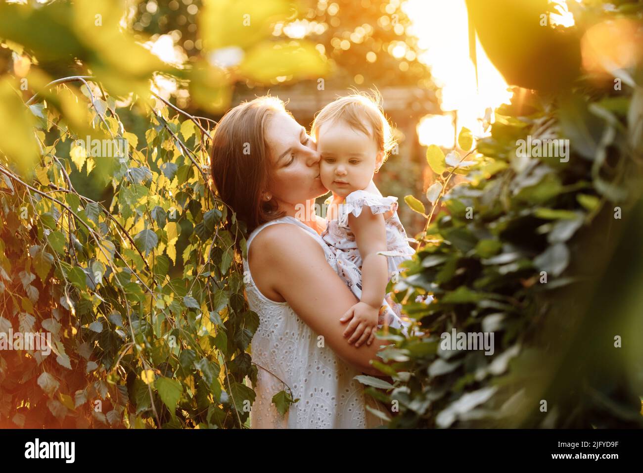 Happy young mother playing and kissing her little baby daughter on ...