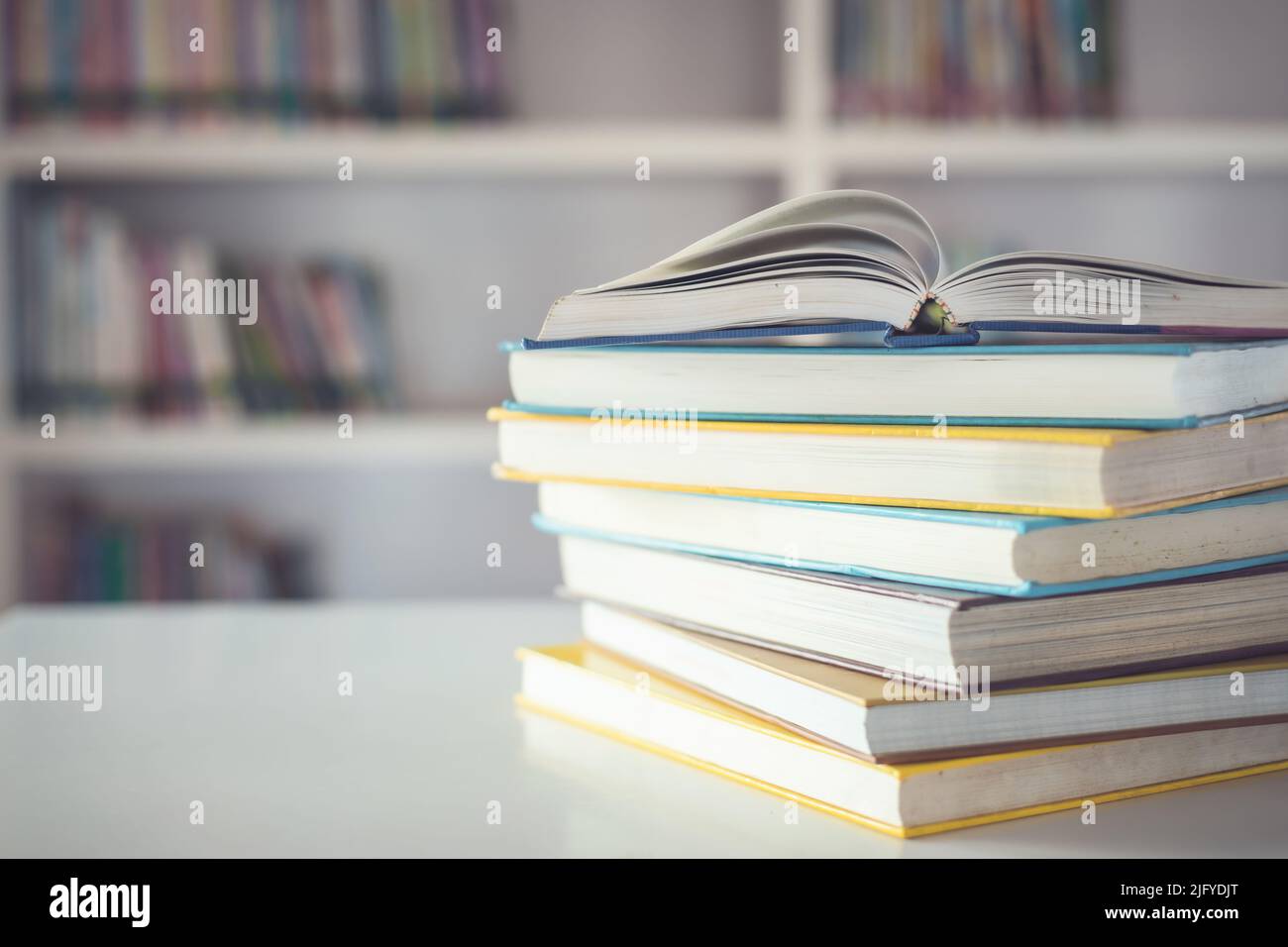 Close up book stack on the table in the library room and blurred space ...
