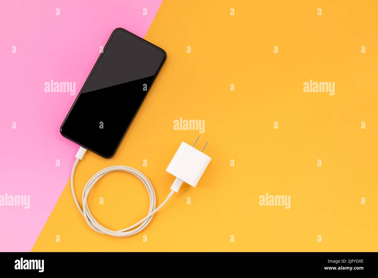 Top view new smartphone with white charger on color background with ...