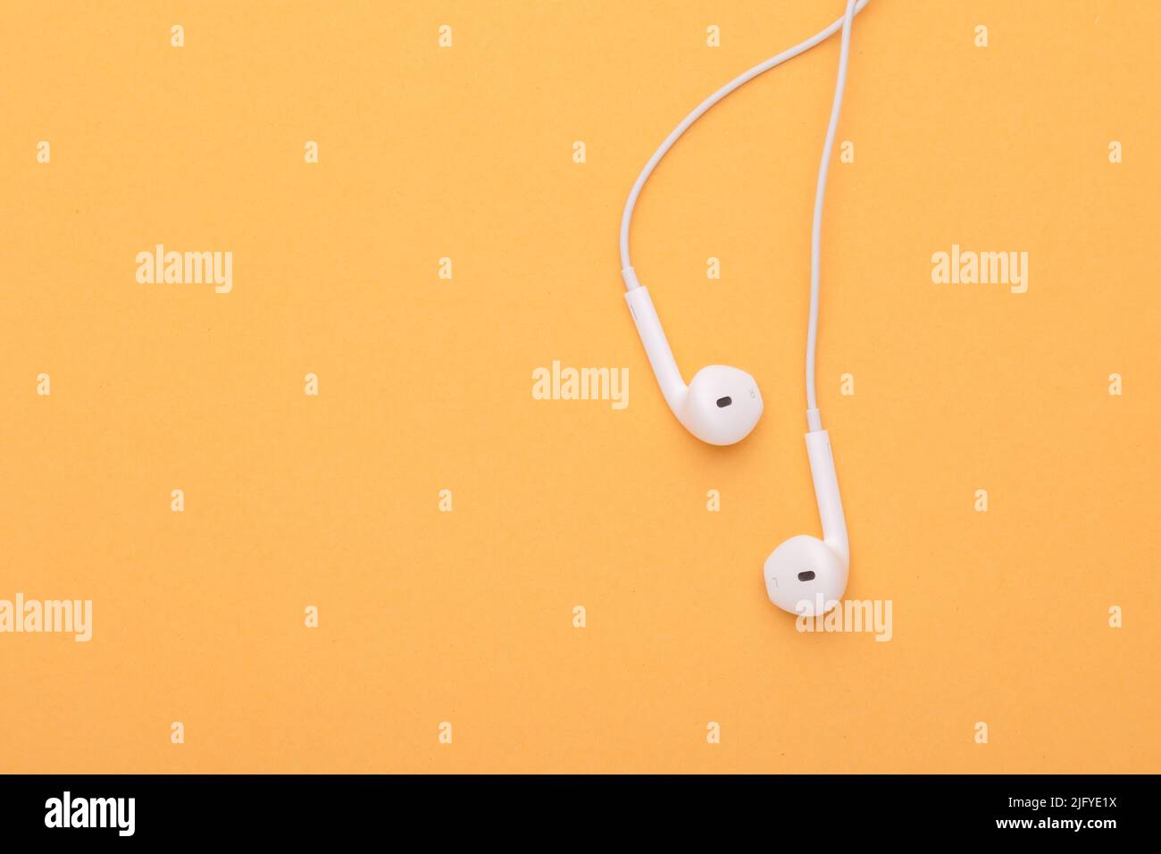 Top view white earphone on yellow background. Copy space for text or ...