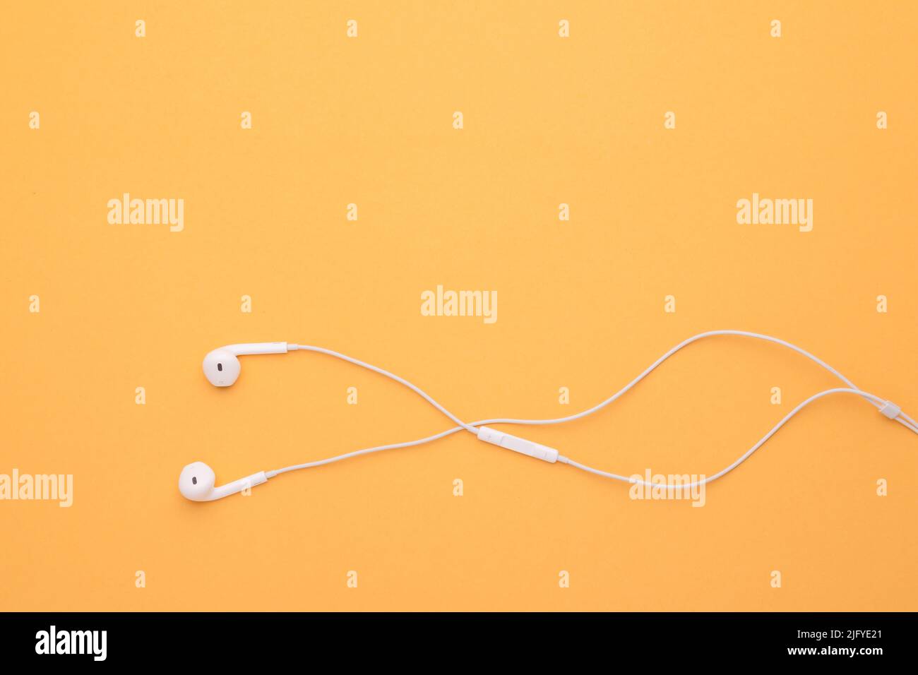Top view white earphone on yellow background. Copy space for text or ...