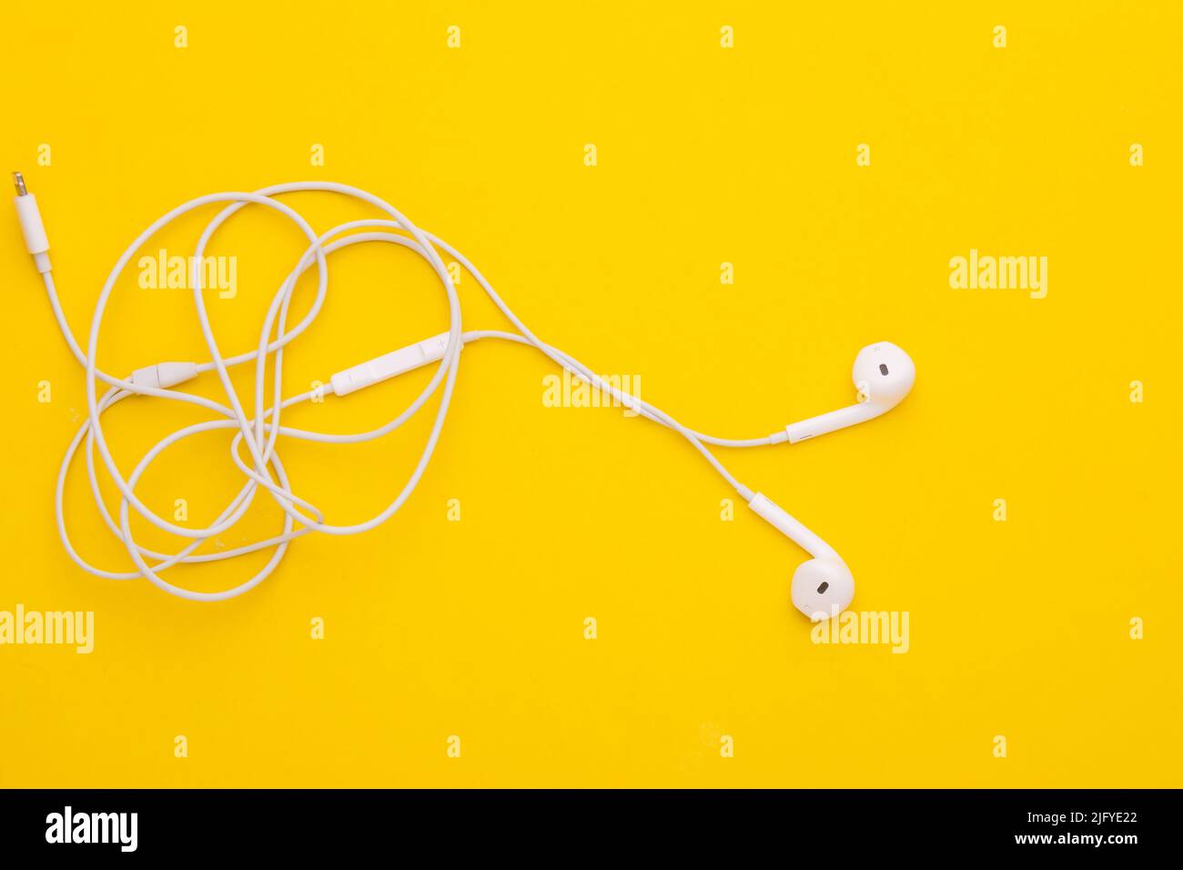 Top view white tangle earphone on yellow background. Copy space for ...