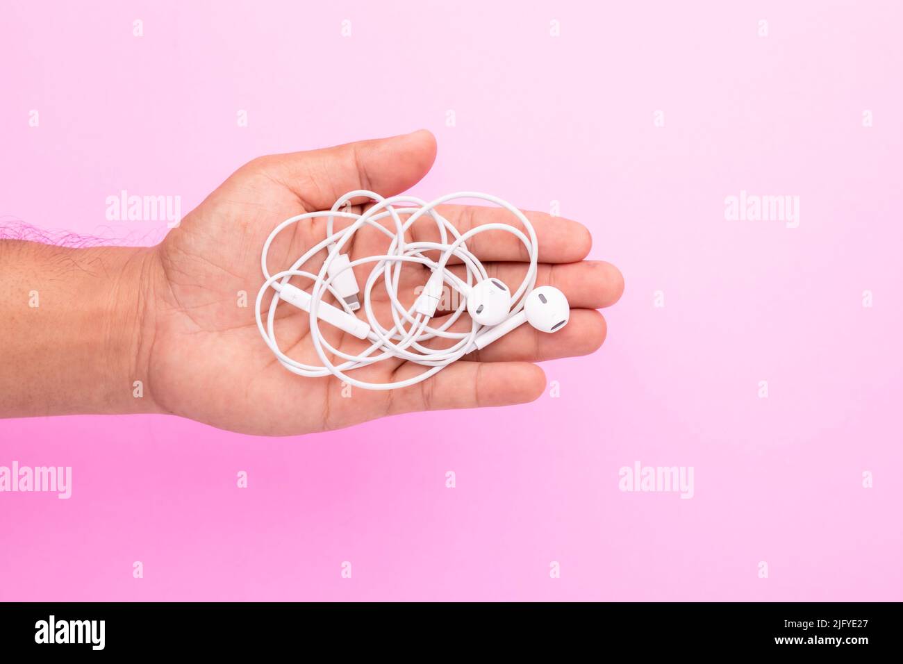 Top view white tangle earphone in hand on pink background. Copy space ...