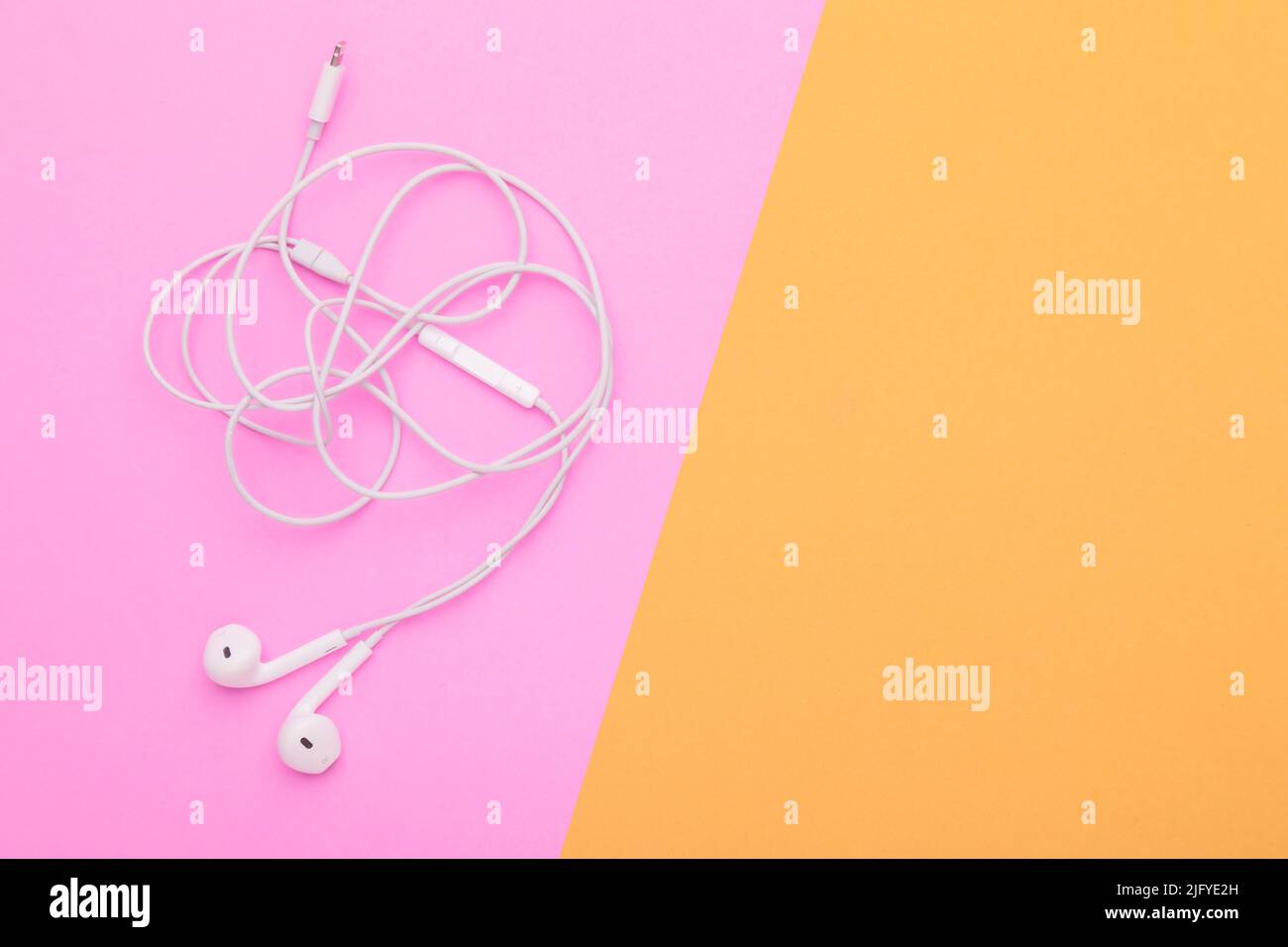 Top view white tangle earphone on pink background. Copy space for text ...