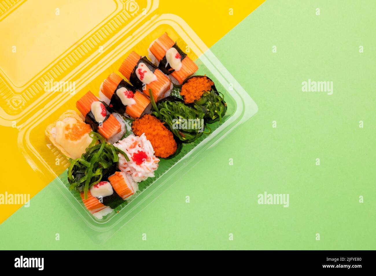 Top view Japanese food (sushi) in clear plastic food box on yellow ...