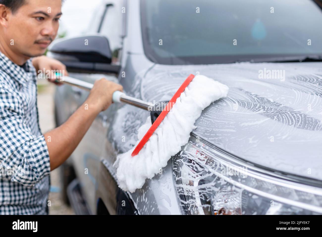 Asian man using white mop with soap to washing the car at outdoor. Car ...