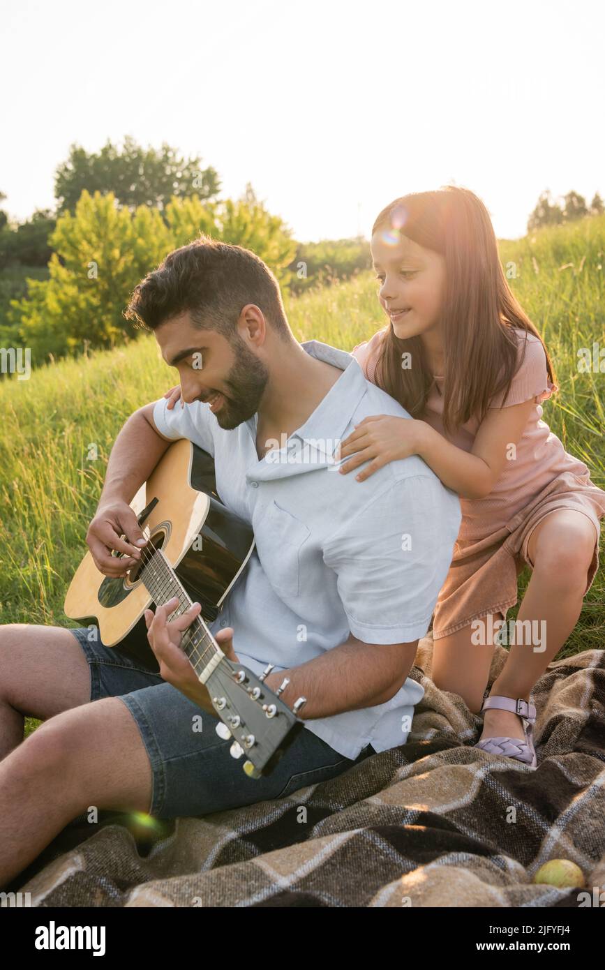 smiling girl hugging shoulders of dad playing guitar while resting in ...