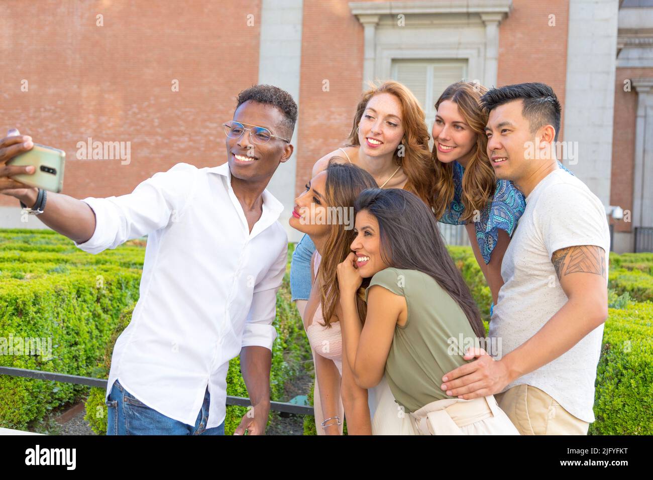 Multiracial group of friends taking a selfie with mobile int he street ...