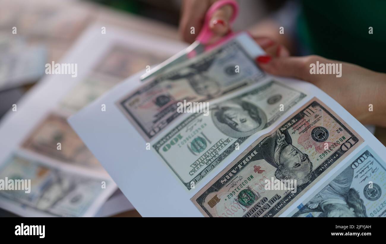 Female hands cutting out dollar bills printed on printer with scissors ...