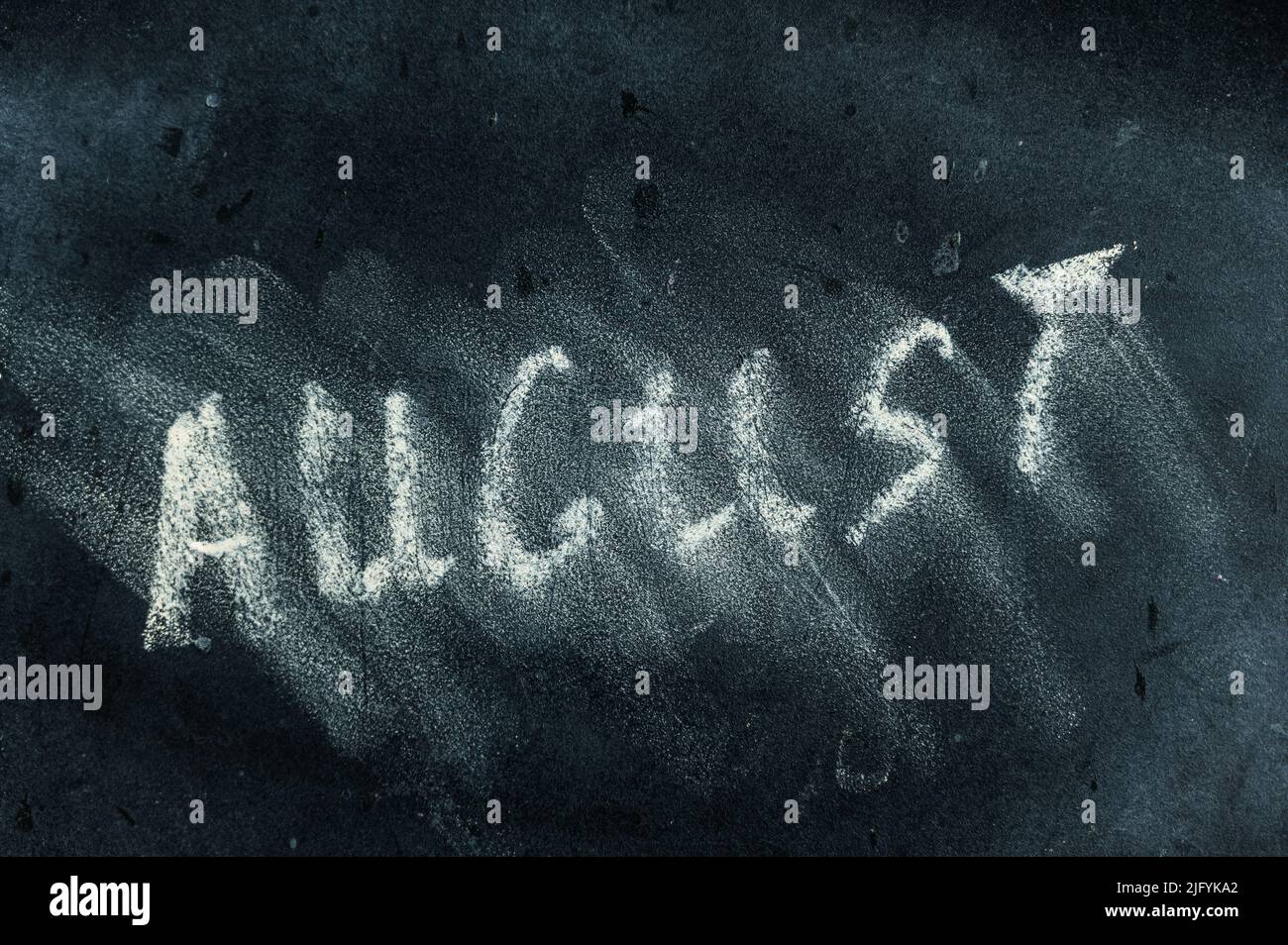 Semi-erased word AUGUST on black chalkboard. Handwritten word. Fuzzy ...