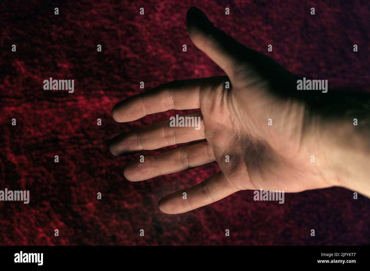The open palm of a mature man against a dark red background. Gesture of ...