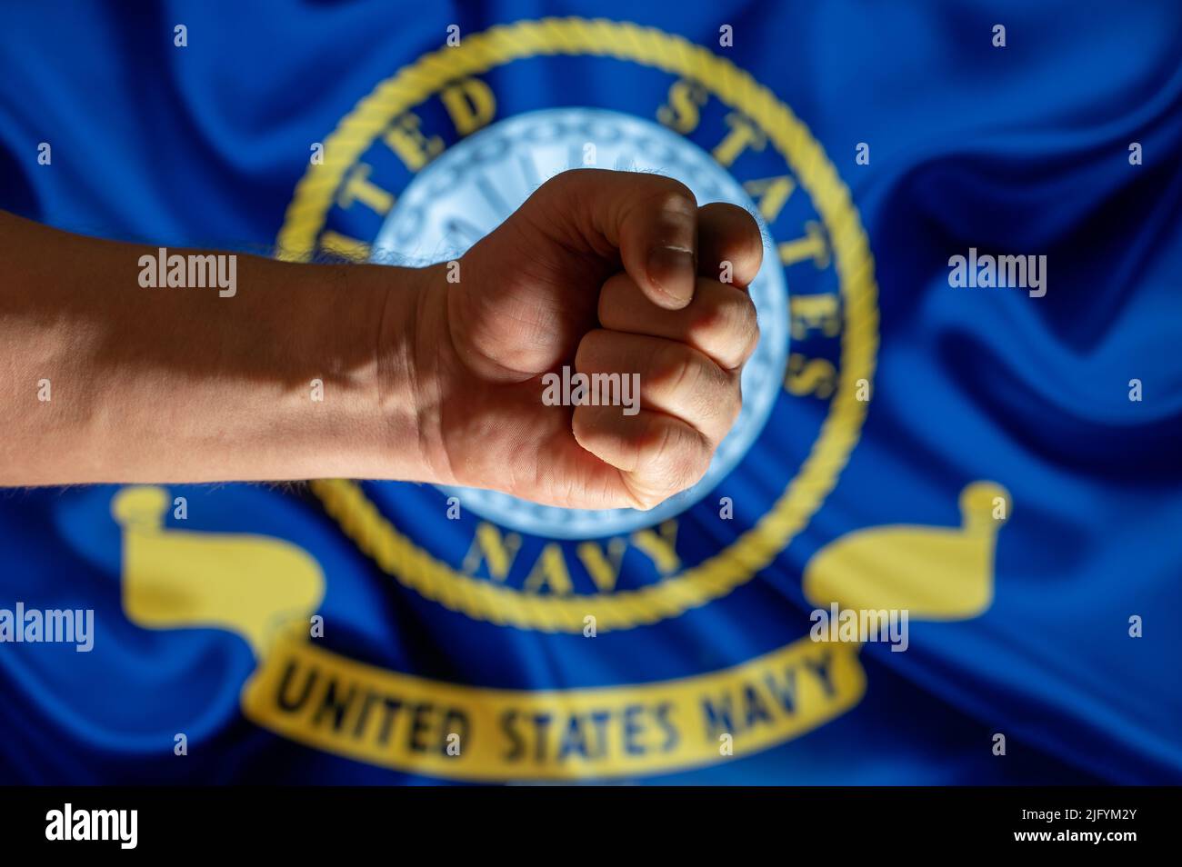 A man's fist on the background of the U.S. Navy flag. A firmly clenched ...
