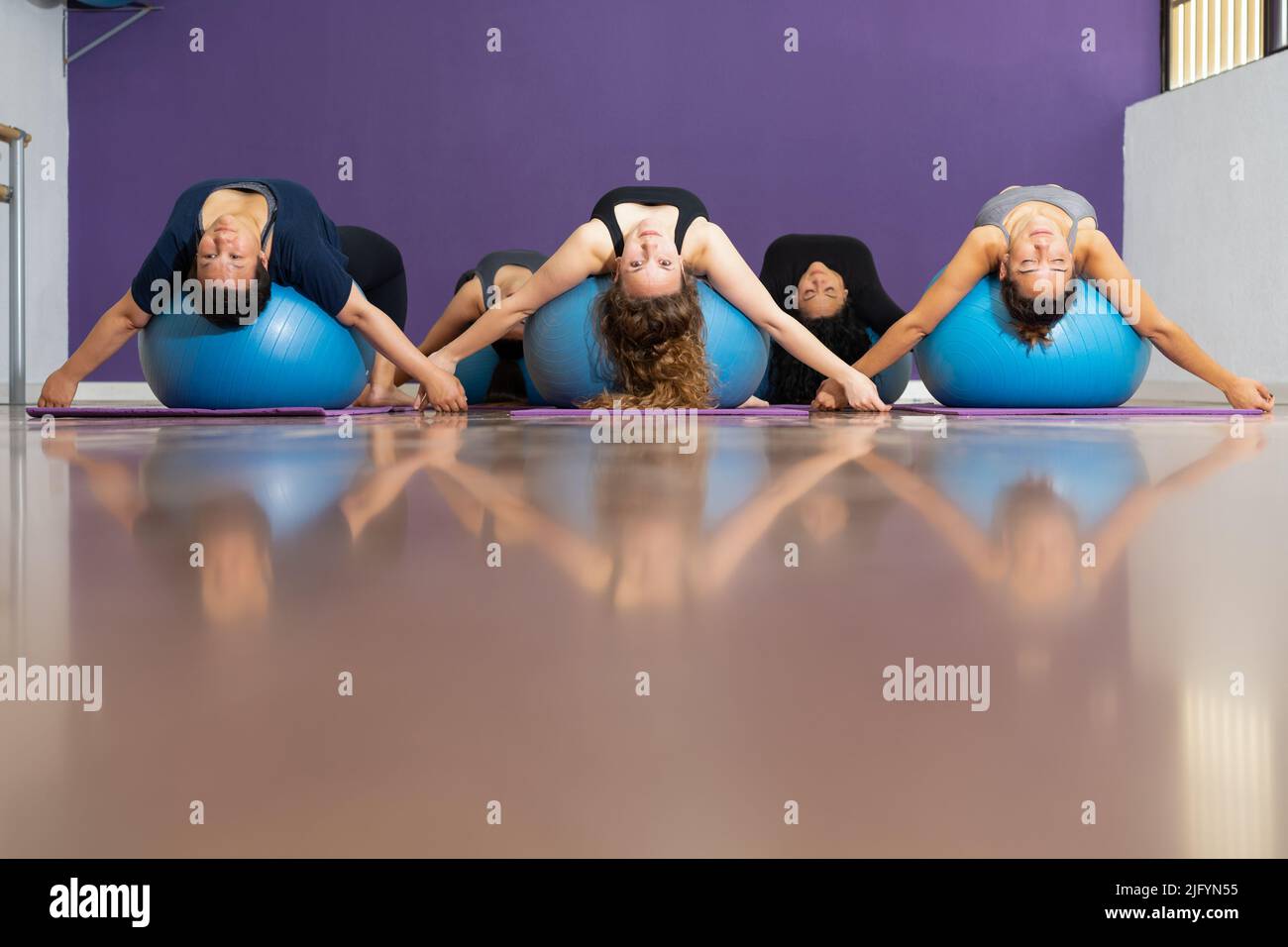Group of women practicing pilates while doing exercise on a ball ...