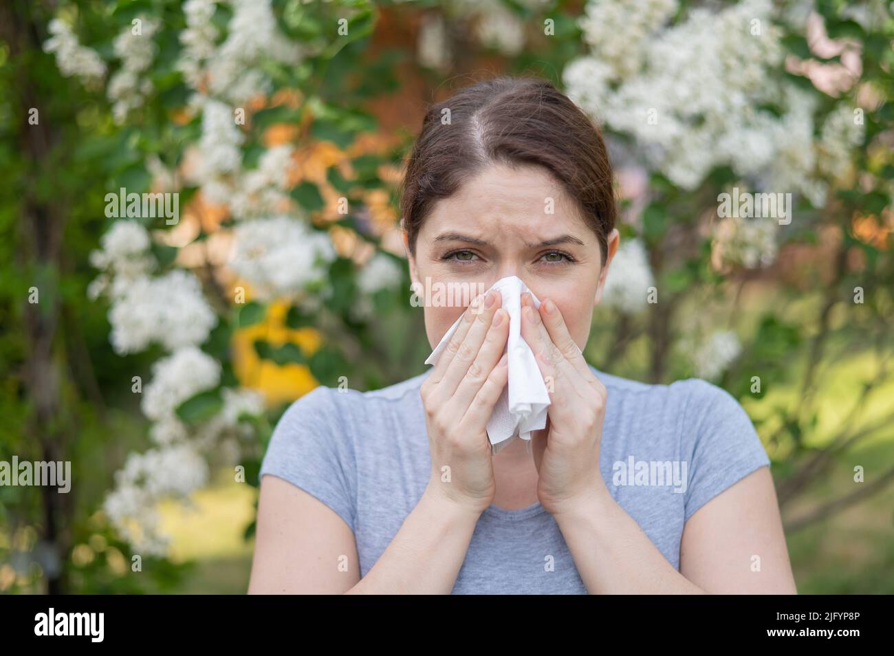 Caucasian woman suffers from allergies and blows her nose into a napkin ...