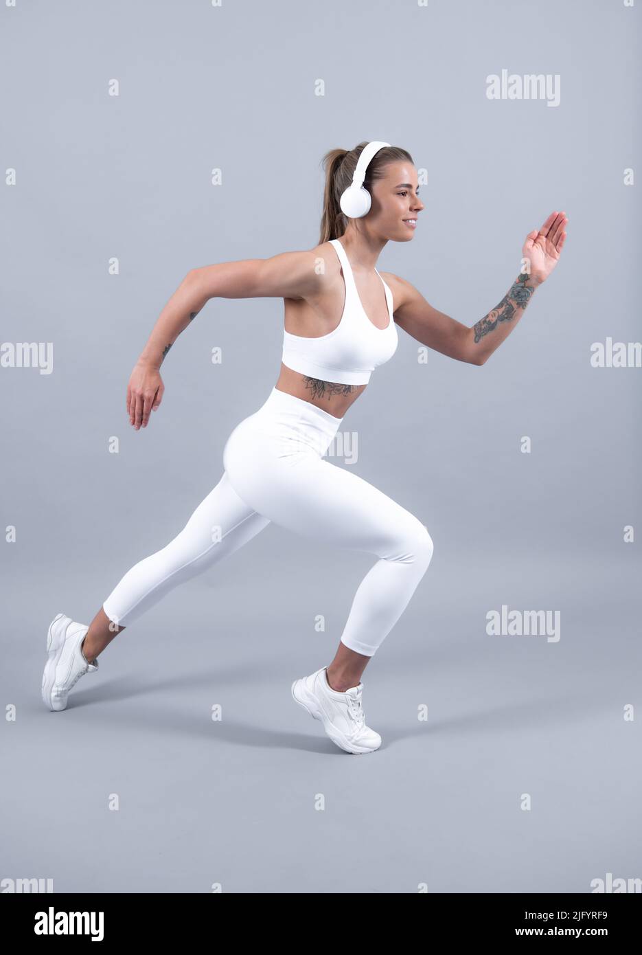 Young fitness woman runner with headphone run, isolated on gray ...