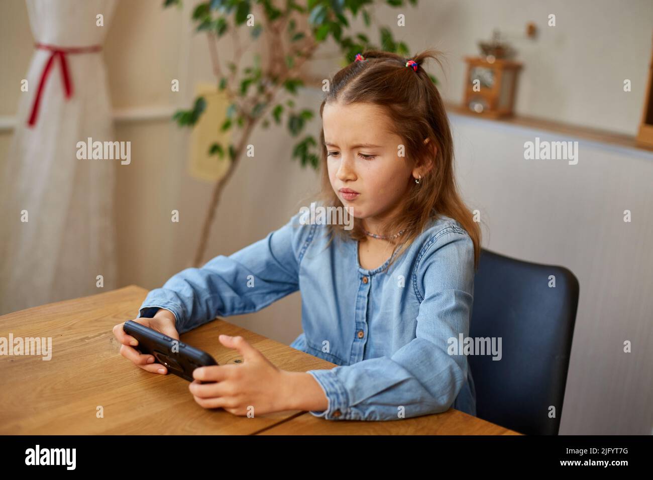 Happy kid girl playing game on mobile phone at home, child using ...
