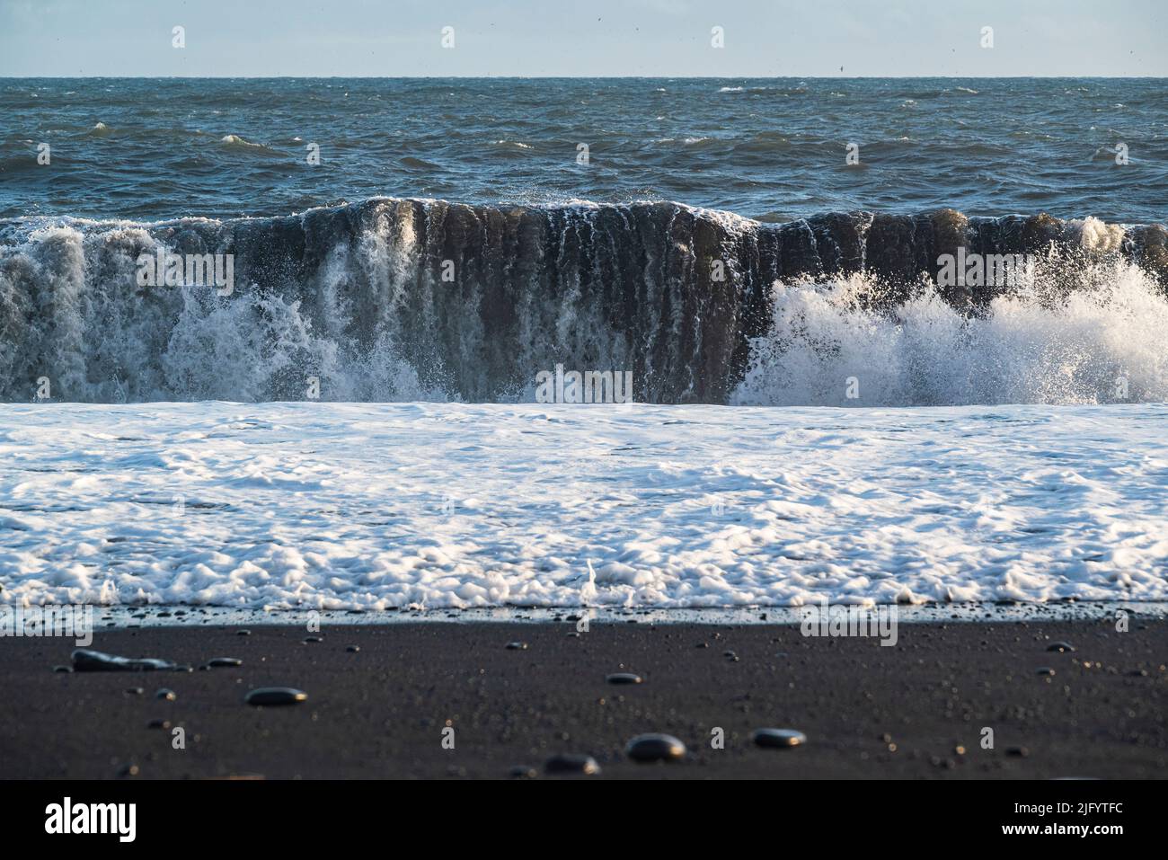 Mighty ocean wave rolling towards the black lava sand of the famous ...