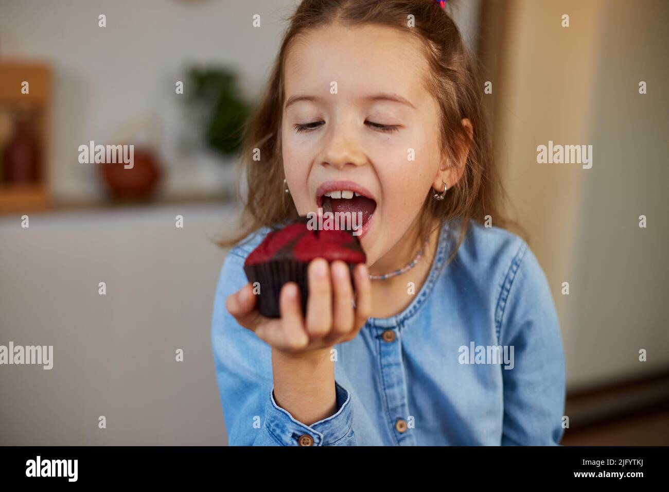Happy emotional little girl eats cupcake at home, smiling happy ...