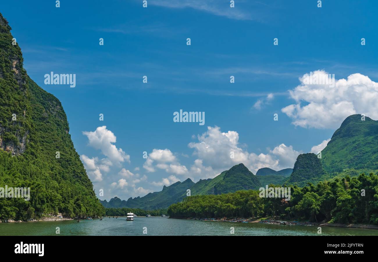 Sightseeing boat carrying tourists sailing among high vertical cliffs ...