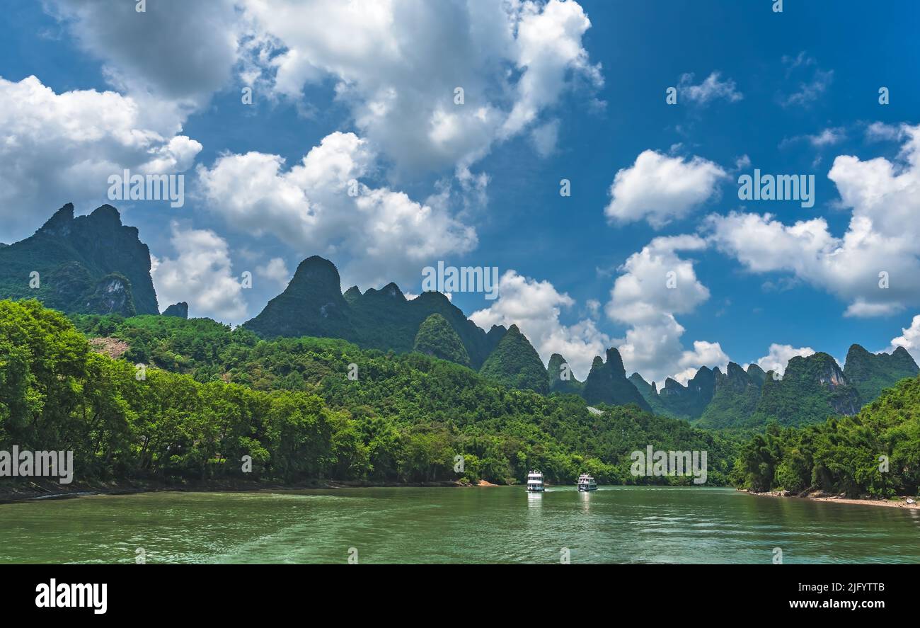 Sightseeing boats carrying tourists sailing among high vertical cliffs ...