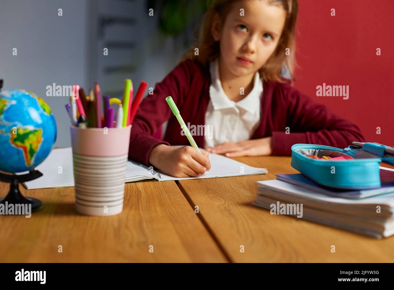 Focused schoolgirl sit at desk doing homework handwriting ...