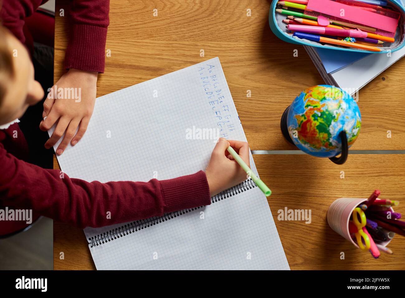 Focused schoolgirl sit at desk doing homework handwriting ...