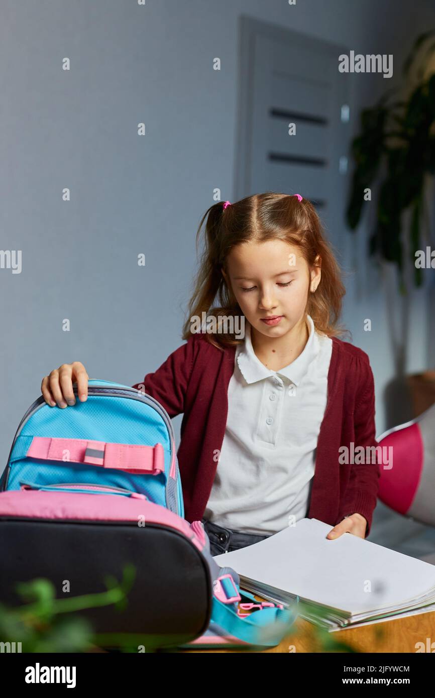 Schoolgirl put books and notes into backpack at home, pupil prepare ...