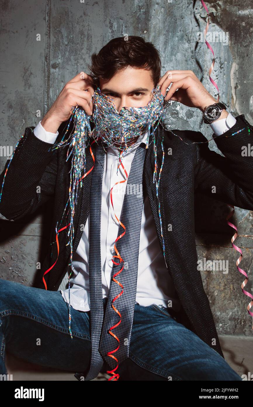 Man closing his face with trumpery at after party Stock Photo - Alamy