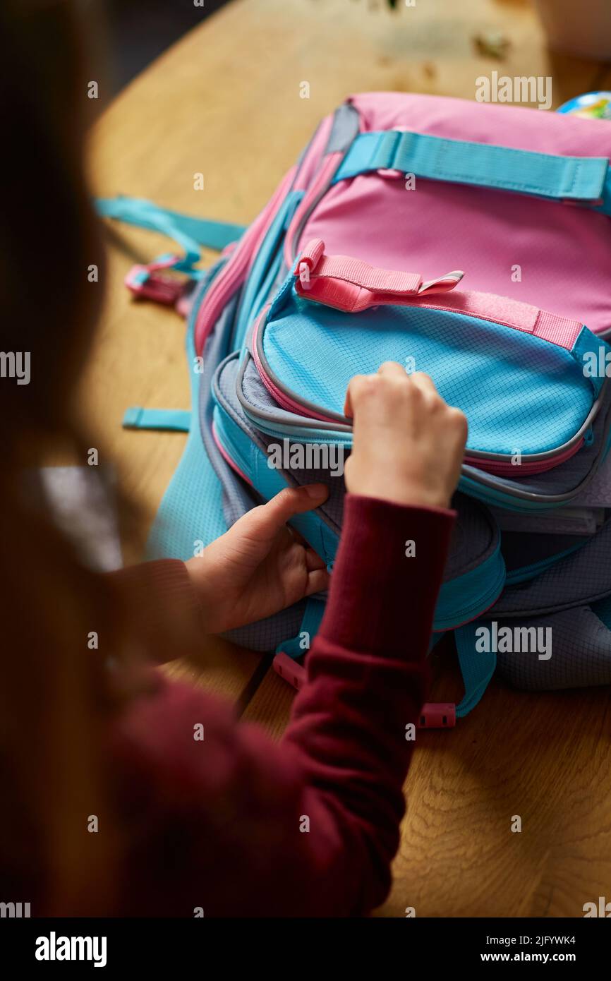 Schoolgirl put books and notes into backpack at home, pupil prepare ...