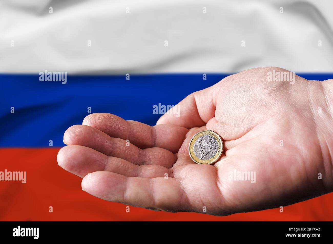 Coin one euro in the hand of a man, the flag of Russian Federation on ...