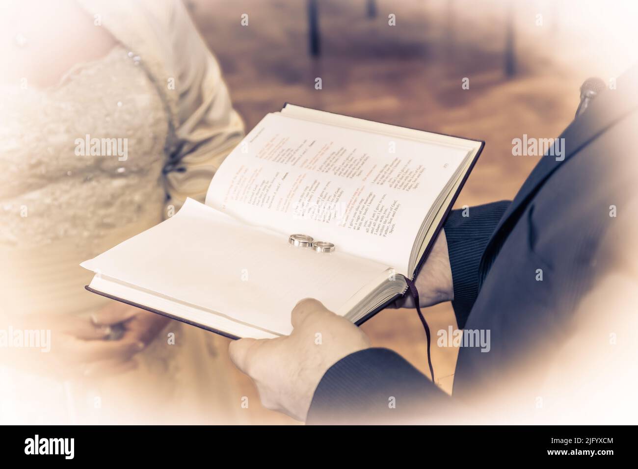 Wedding rings on a Bible presented by priest to the newlyweds bride and ...