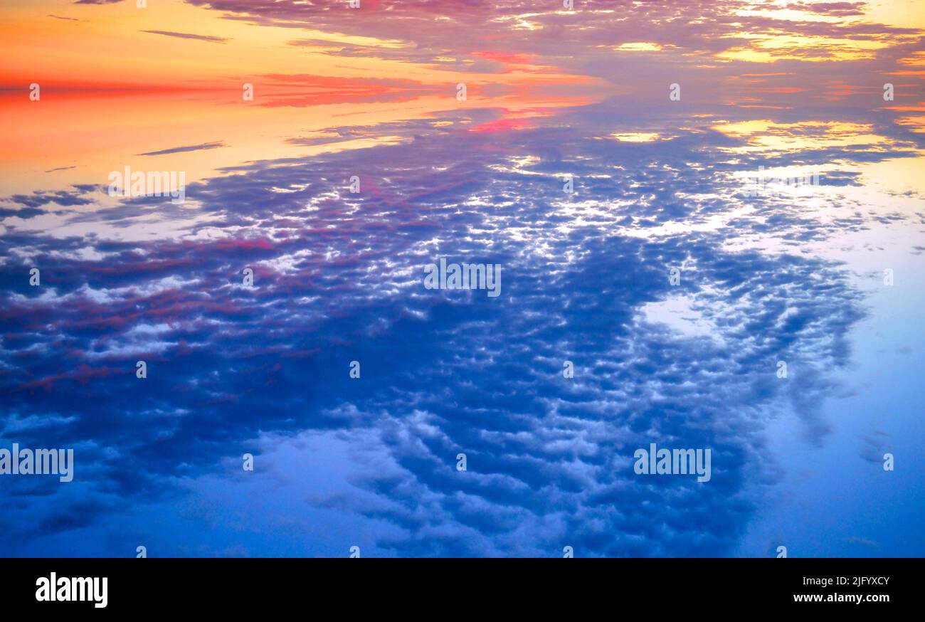 Horizontal picture of clouds in the sky reflected in a calm sea surface ...