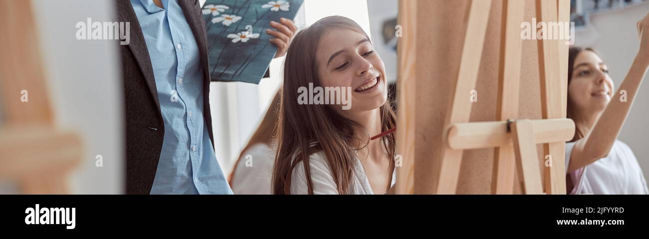 Young creative happy pupils at light modern classroom are doing drawing ...